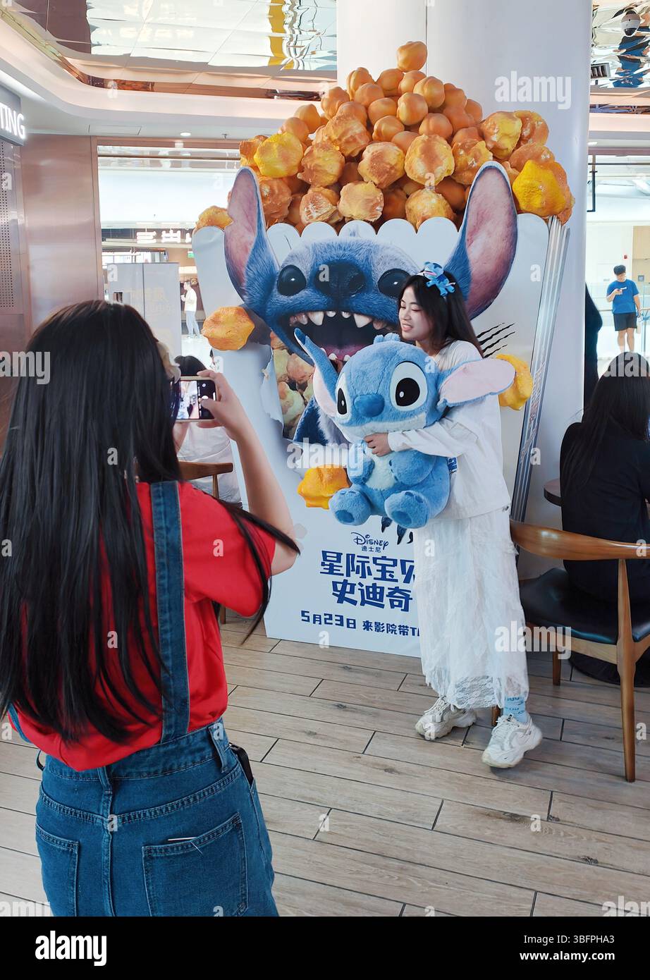SHANGHAI, CHINA - JUNE 2, 2025 - A Movie fan poses for a photo with an alien doll in front of ...