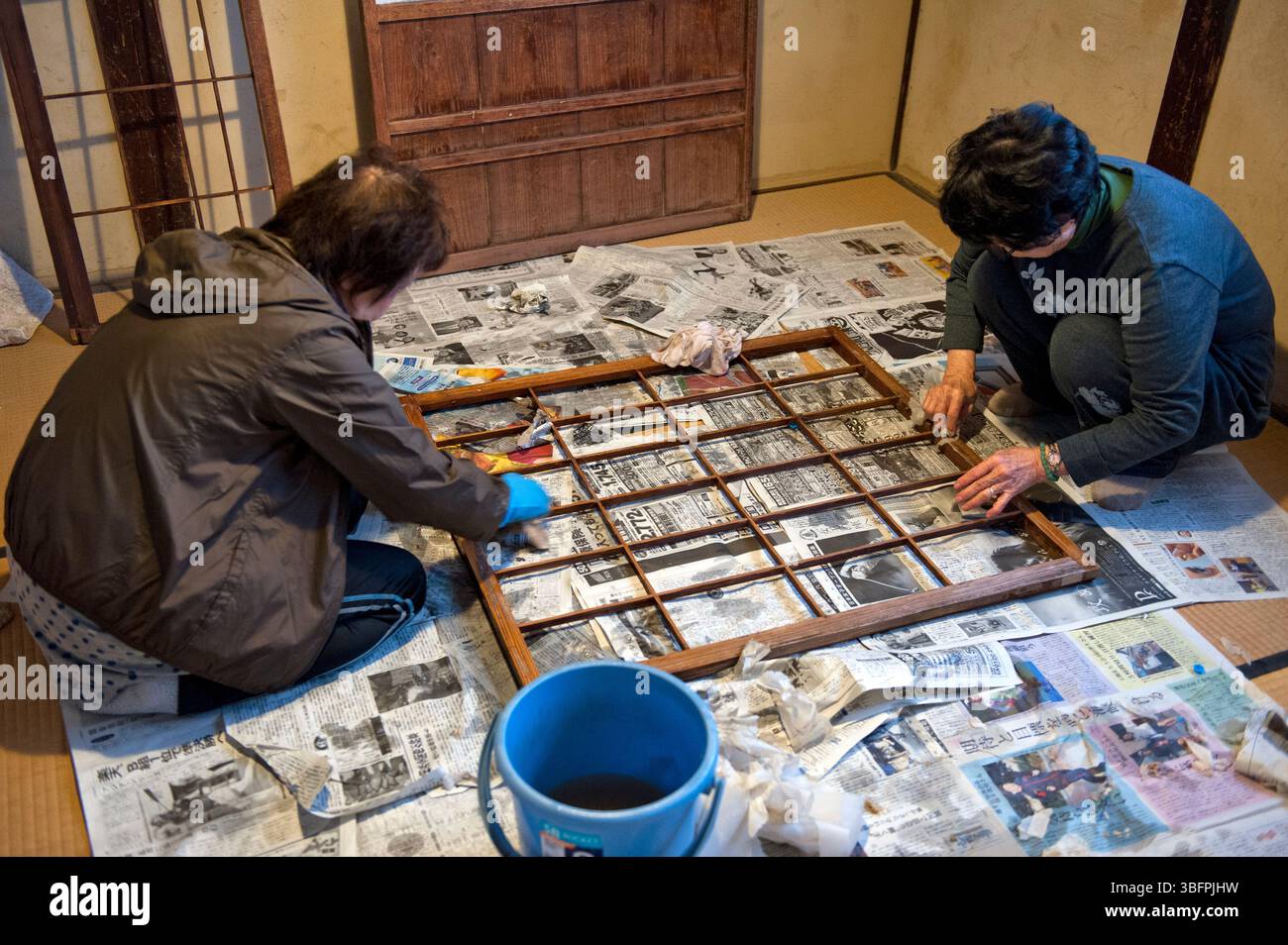 Two senior women replacing the washi paper on a shoji sliding screen in ...