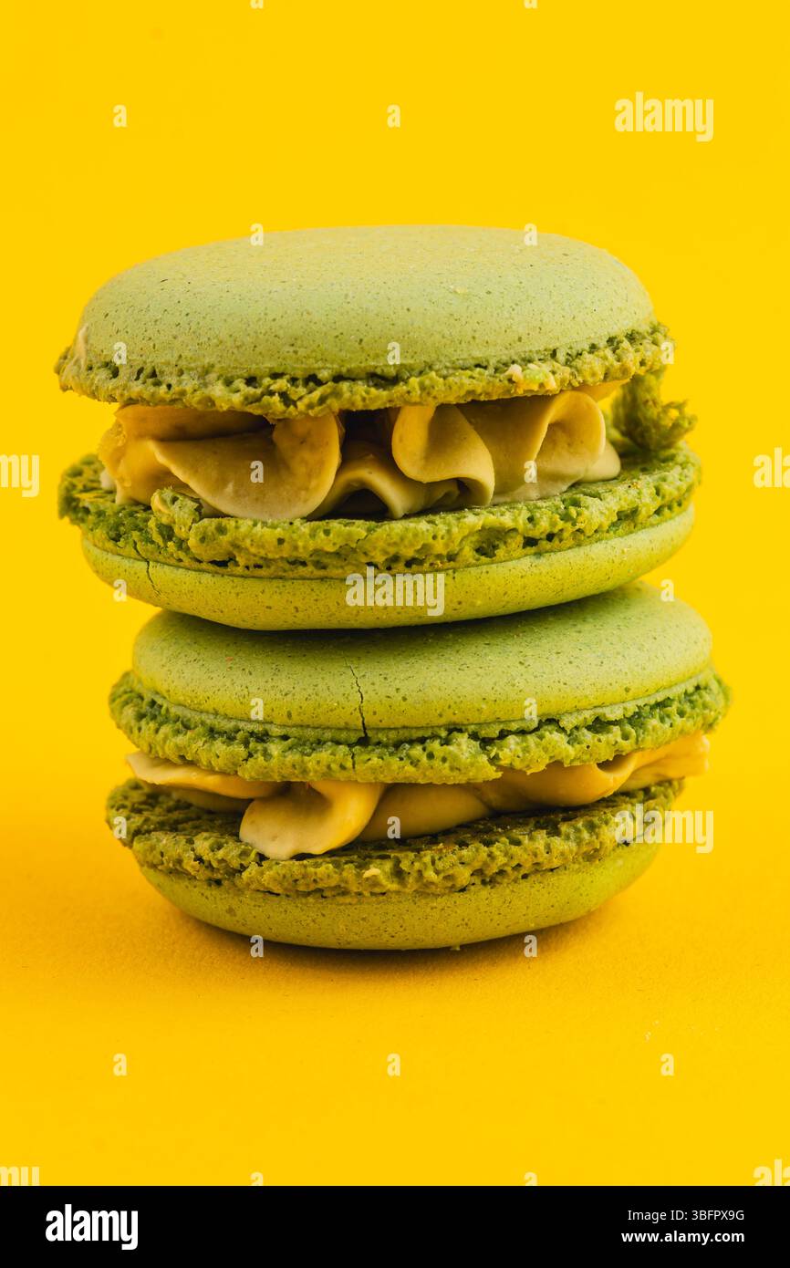 Two stacked green macarons with a creamy filling sit against a bright ...