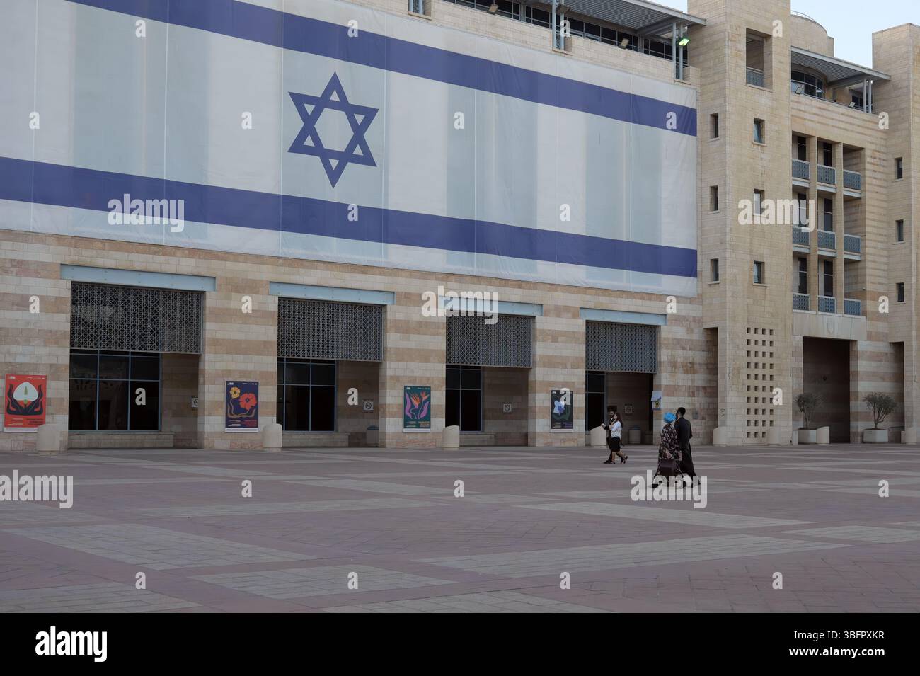 Ultra-Orthodox Jews walk past a large Israeli flag displayed on the ...