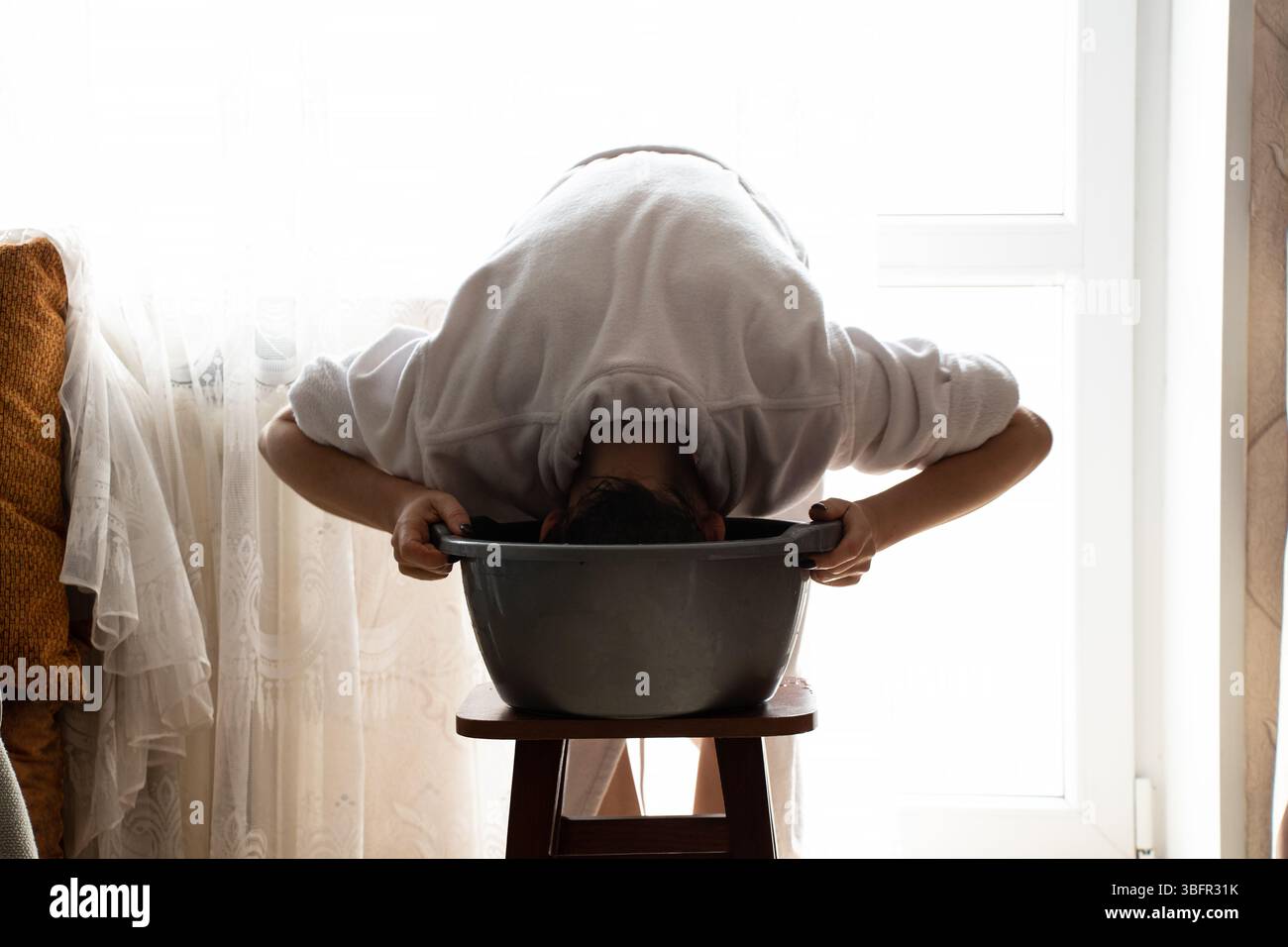 Girl washes hair in a basin at home, self-care at home without a shower ...