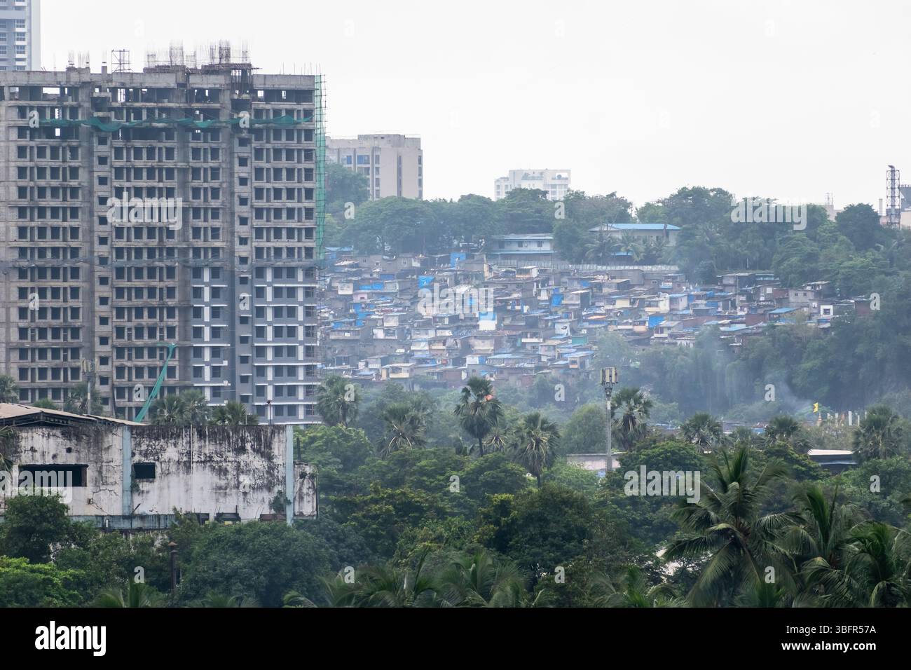 In Mumbai, a modern high-rise building overlooks a sprawling slum area ...