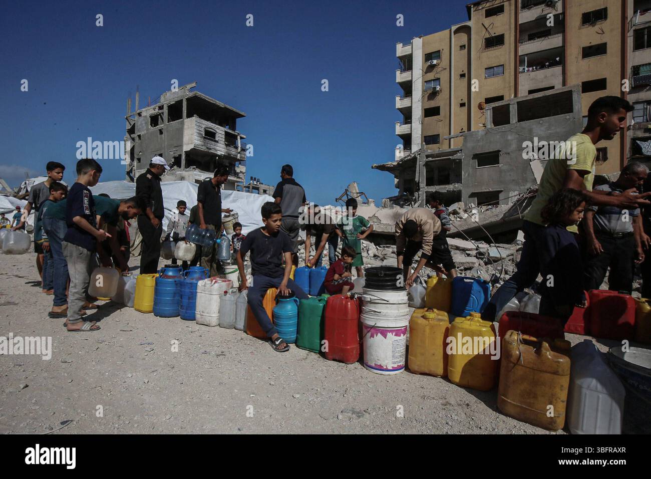 Palestinians carry jerry cans filled with water distributed by a water ...