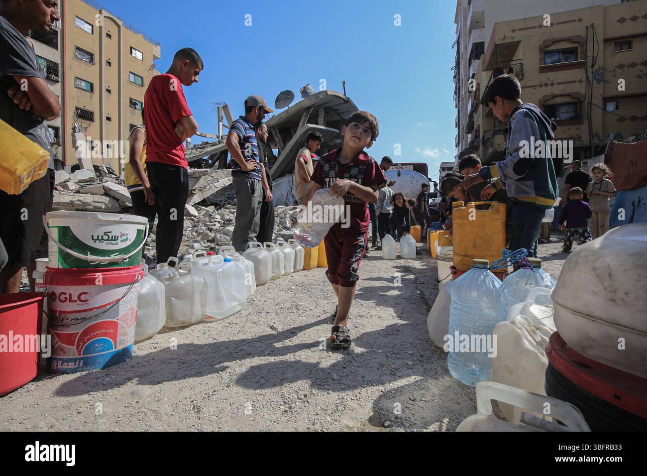 Palestinians carry jerry cans filled with water distributed by a water ...