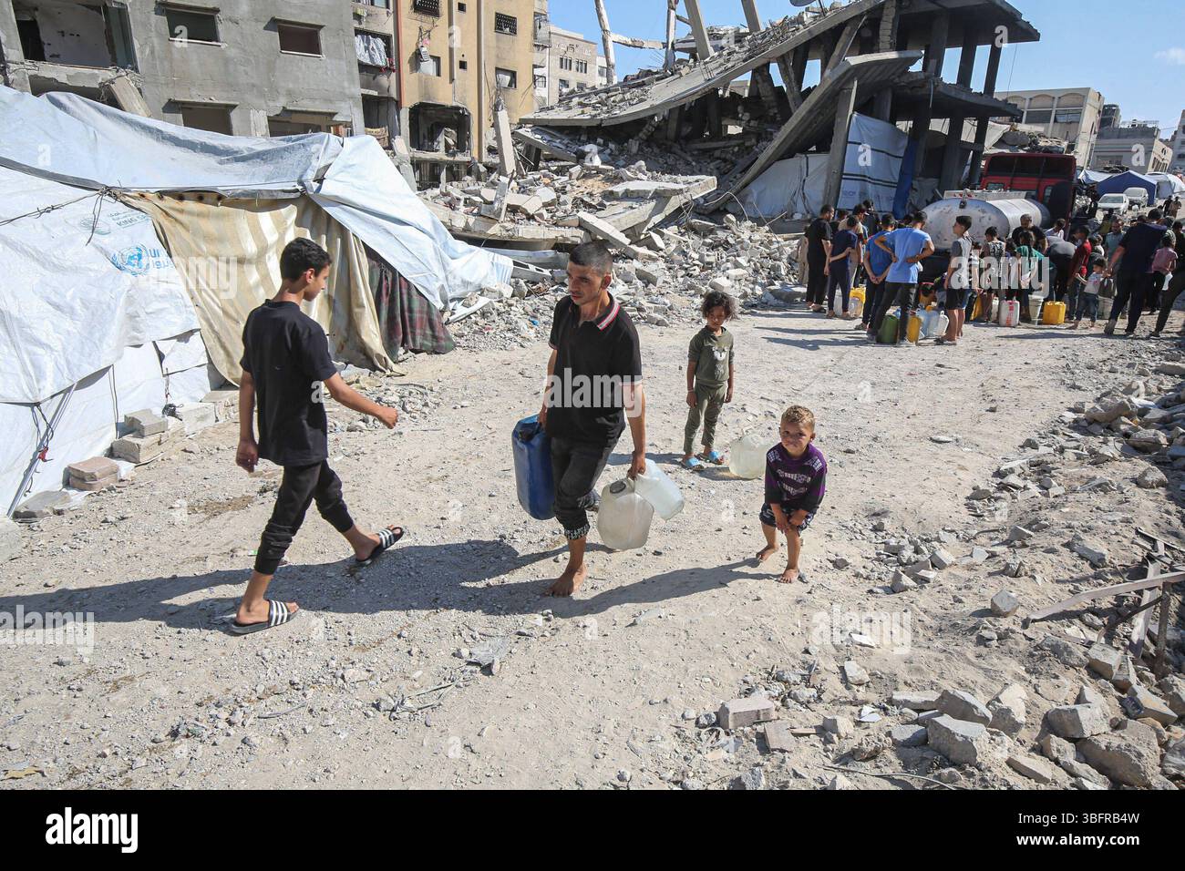 Palestinians carry jerry cans filled with water distributed by a water ...