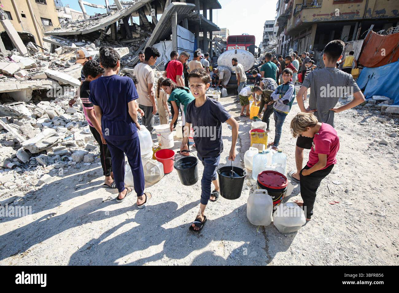 Palestinians carry jerry cans filled with water distributed by a water ...
