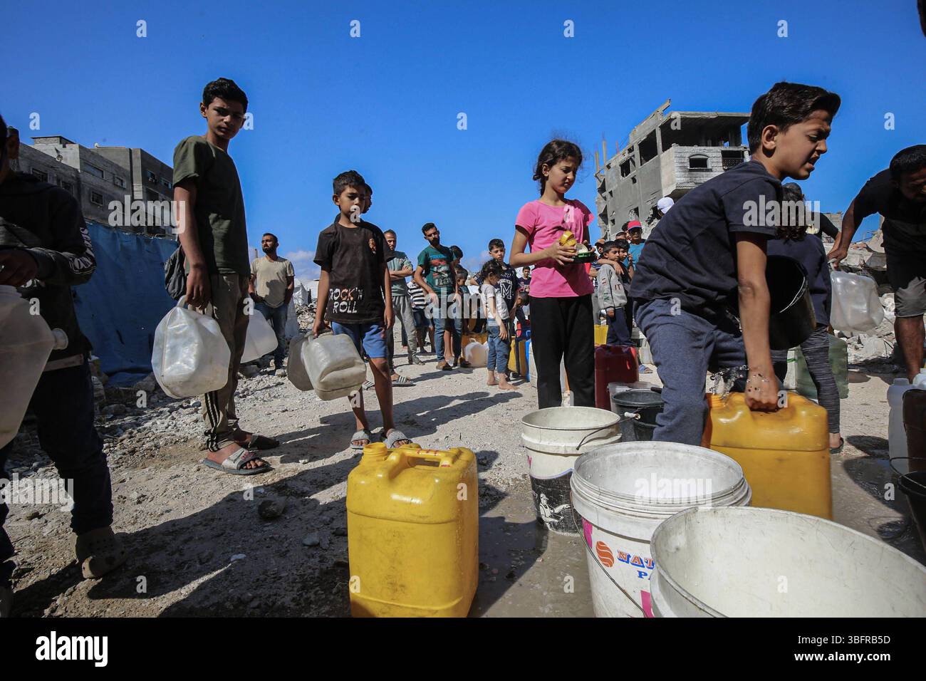 Palestinians carry jerry cans filled with water distributed by a water ...