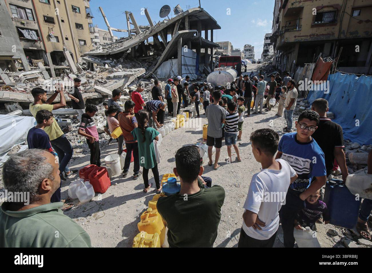 Palestinians carry jerry cans filled with water distributed by a water ...