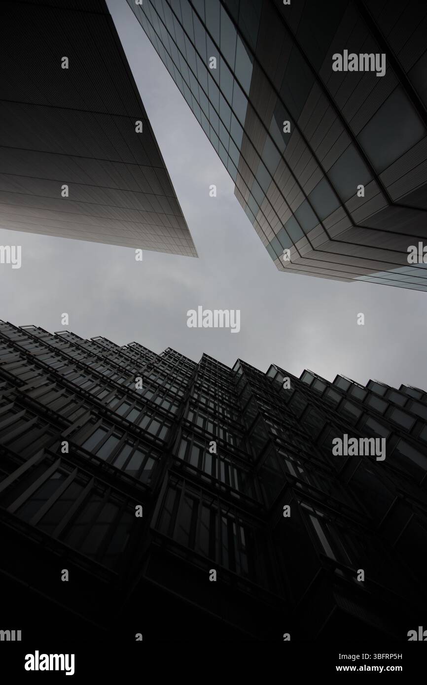 A dramatic upward view of modern skyscrapers in London, showcasing dark ...