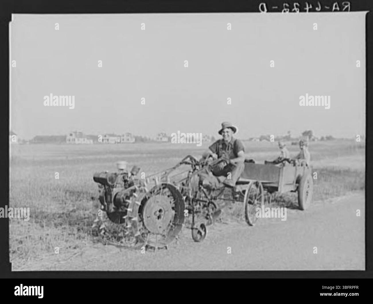 The image shows a homesteader using a garden tractor on farmland. This ...