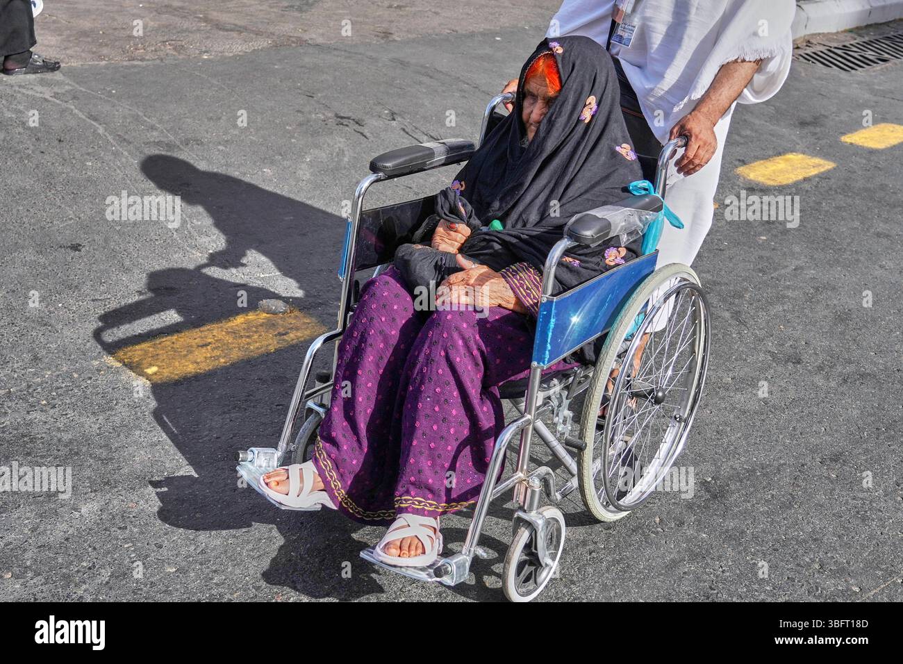 An Afghan elderly pilgrim on wheel chair is pushed by her son, Mawlavi ...