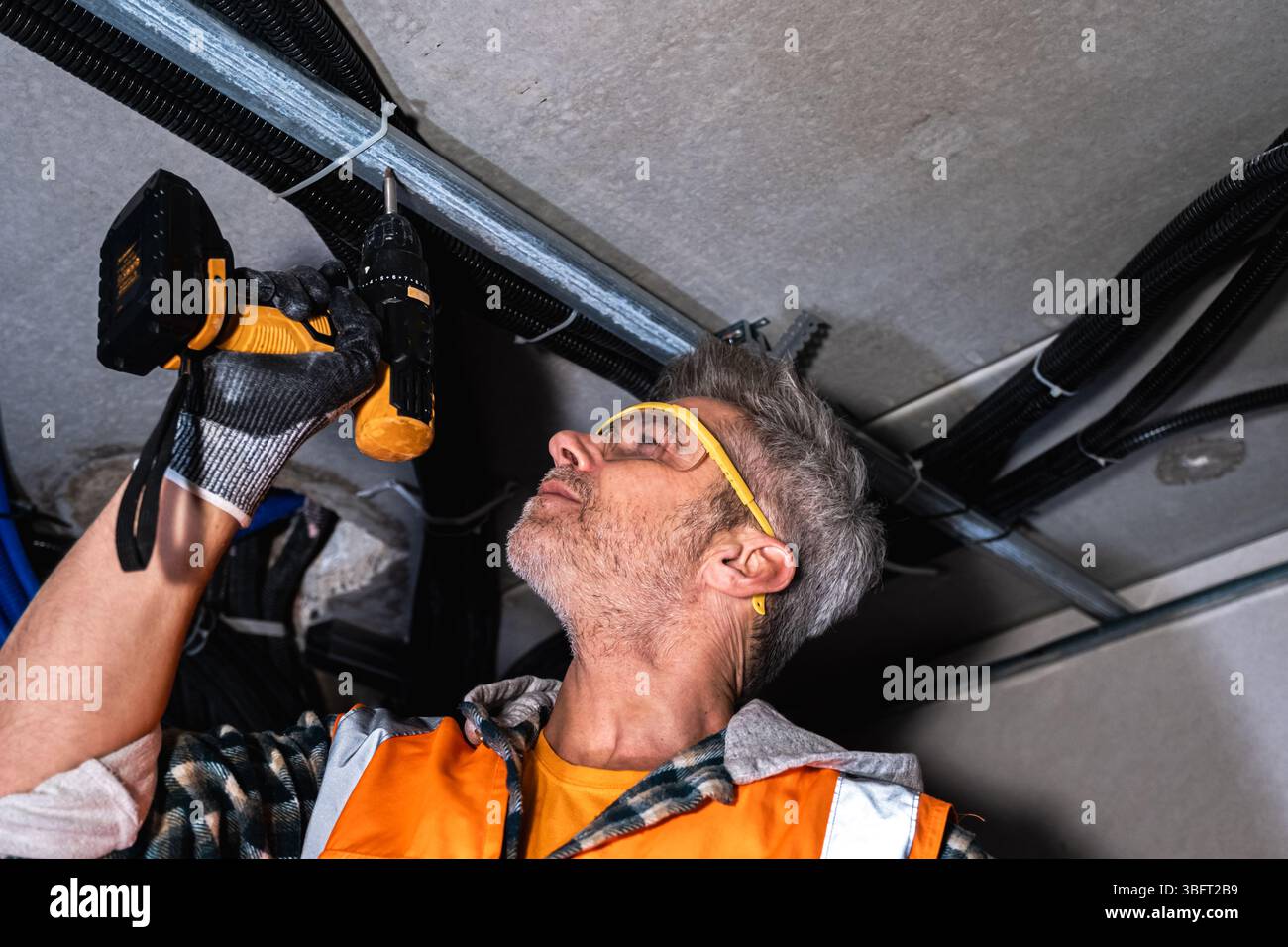 Professional worker using a cordless drill to fasten metal framing to ...