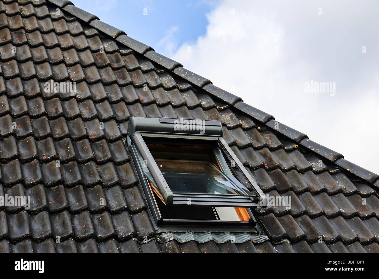 Open roof window on a tiled roof, allowing natural light and fresh air ...