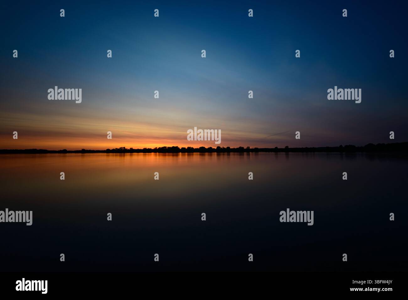 Long exposure waterfront sunset with sun and sky reflection in the ...