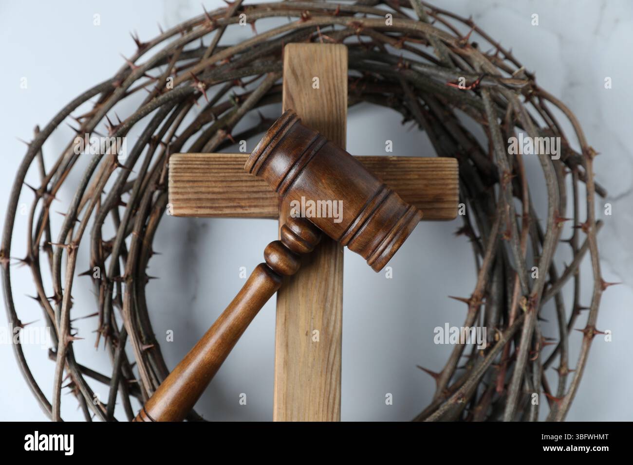 Judge's gavel, wooden cross and crown of thorns on white marble table ...