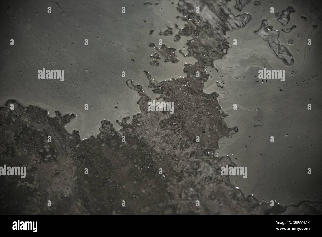 Wet concrete surface with rough texture and glossy patches ...