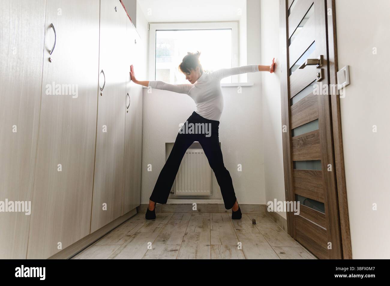 Full-body view of a woman in white top and black pants performing a ...