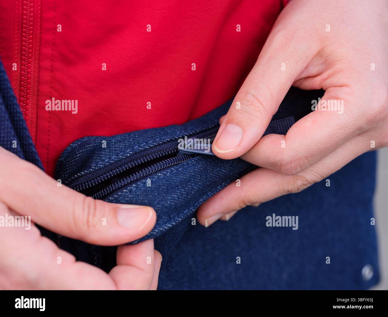 Woman pulling up the zip to open her denim bag Stock Photo - Alamy
