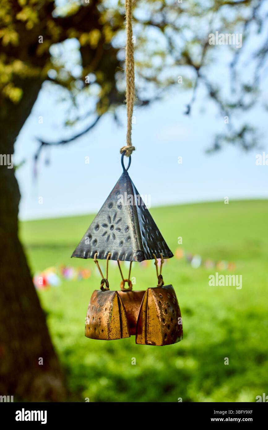 Decorative metal wind chimes hanging from a tree branch, creating a ...