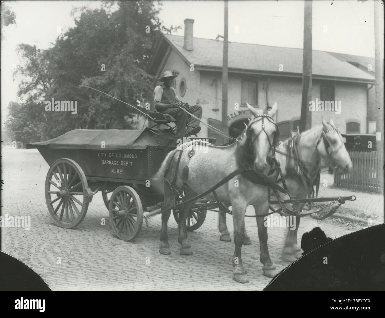 An African American worker is seen atop a horse-drawn garbage wagon ...