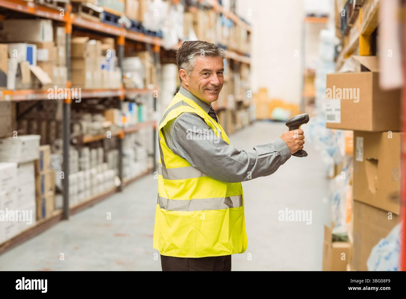 Middle-aged man wearing safety vest scanning boxes with handheld ...