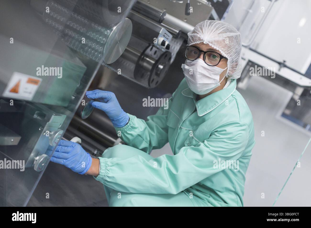Caucasian factory worker in blue lab suit work with machine, sit squat ...