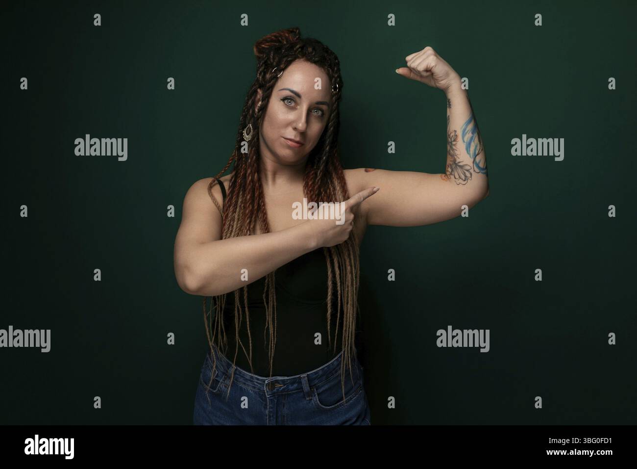 A woman with dreadlocks is standing confidently, striking a pose for a ...
