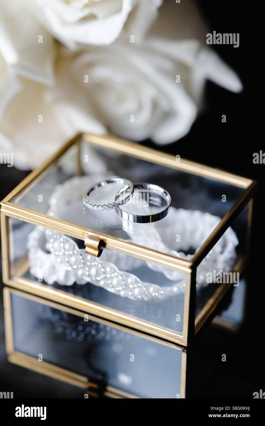 Elegant wedding rings and a garter are displayed in a glass box ...