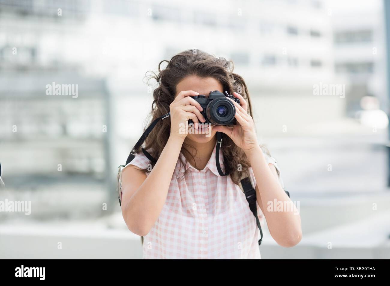 Female photographer raising DSLR camera on rooftop terrace with metal ...