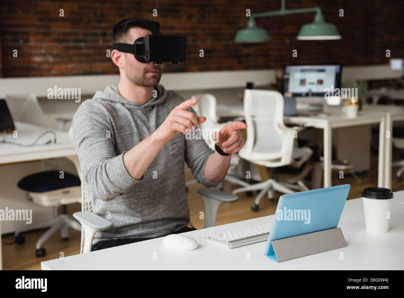 Man wearing virtual reality headset reaching forward at modern office ...