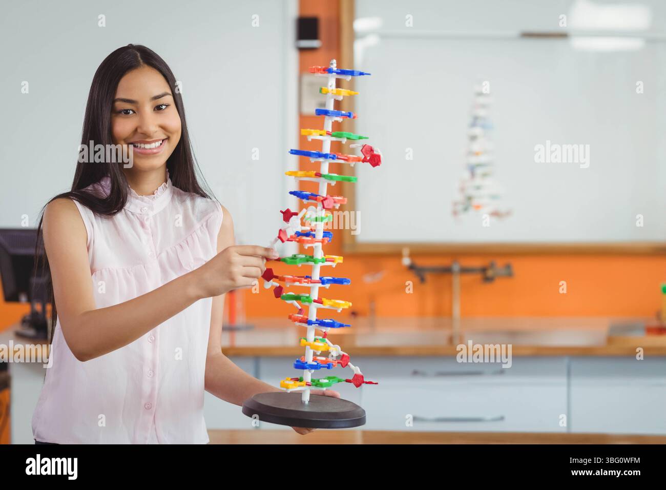 Female student assembling DNA double helix on lab bench in science lab ...