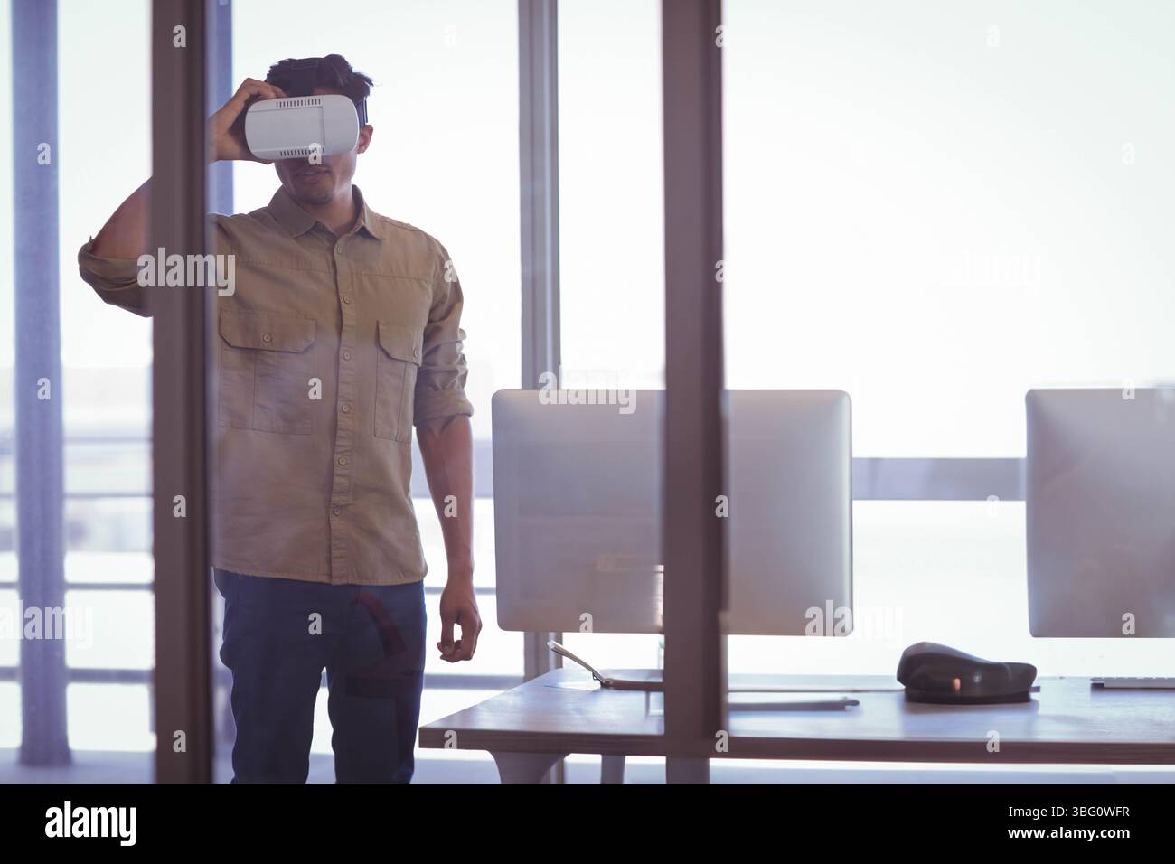 Man wearing VR headset interacting near glass partition in modern ...