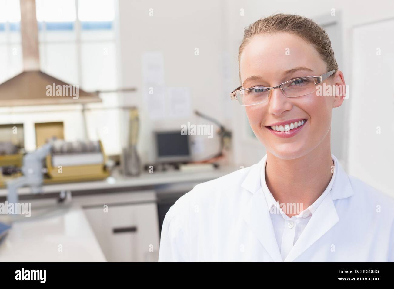 Female lab technician wearing white lab coat analyzing sample at bench ...