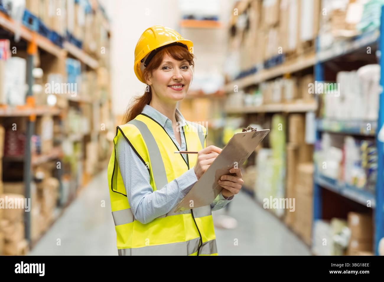 Female warehouse inspector wearing vest with clipboard inspecting ...