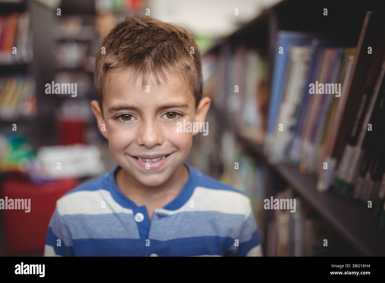 Boy standing in narrow library aisle between wooden bookshelves with ...