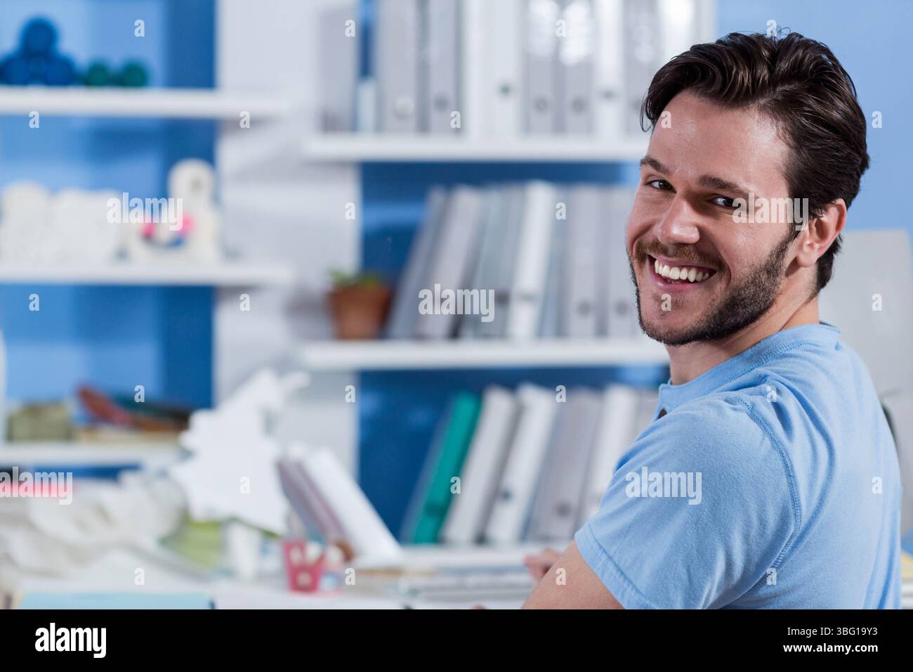Man turning back at desk in bright workspace holding coffee mug and ...