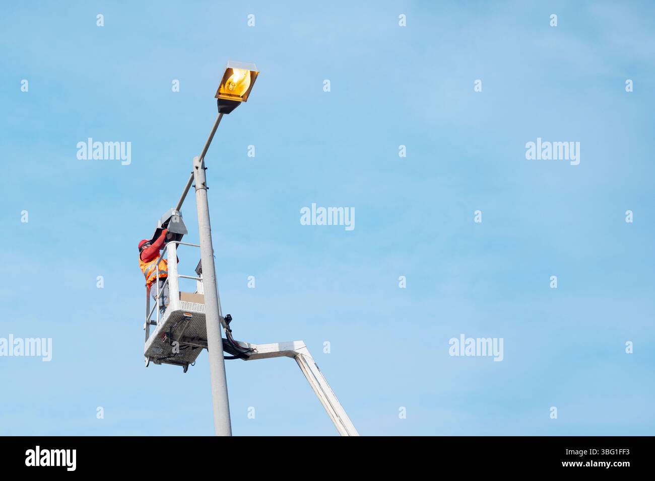 unrecognizable technician on crane changing the lamp of street lamp ...
