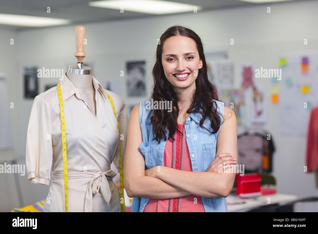 Female designer standing in fashion studio by wrap dress on mannequin ...