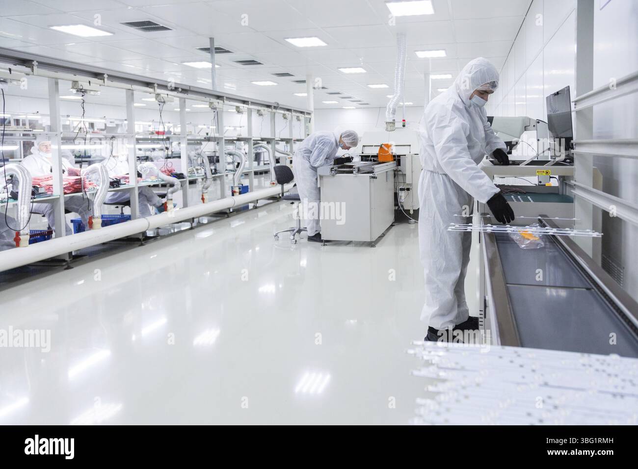 Two factory workers in white lab suits and black latex gloves, working ...