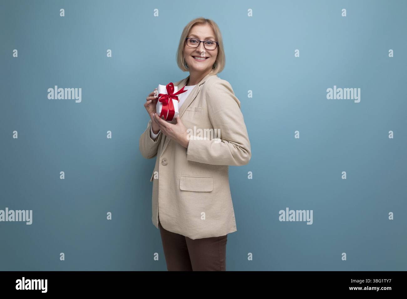 Froehliche 50er jahre reif frau in jacke mit geschenkbox auf studio ...