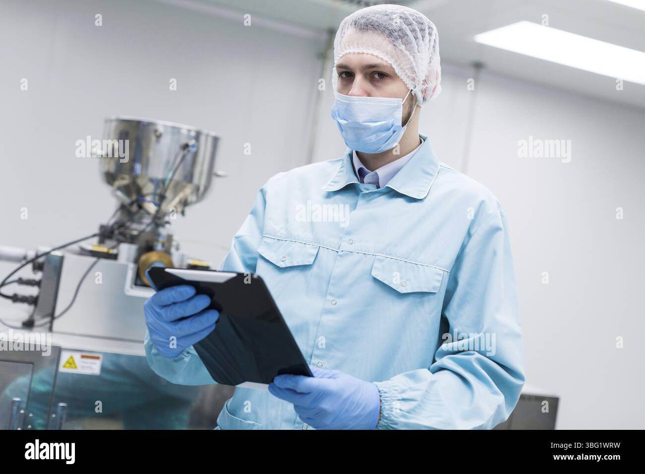 Caucasian scientist man in blue lab suit and gloves work with big metal ...