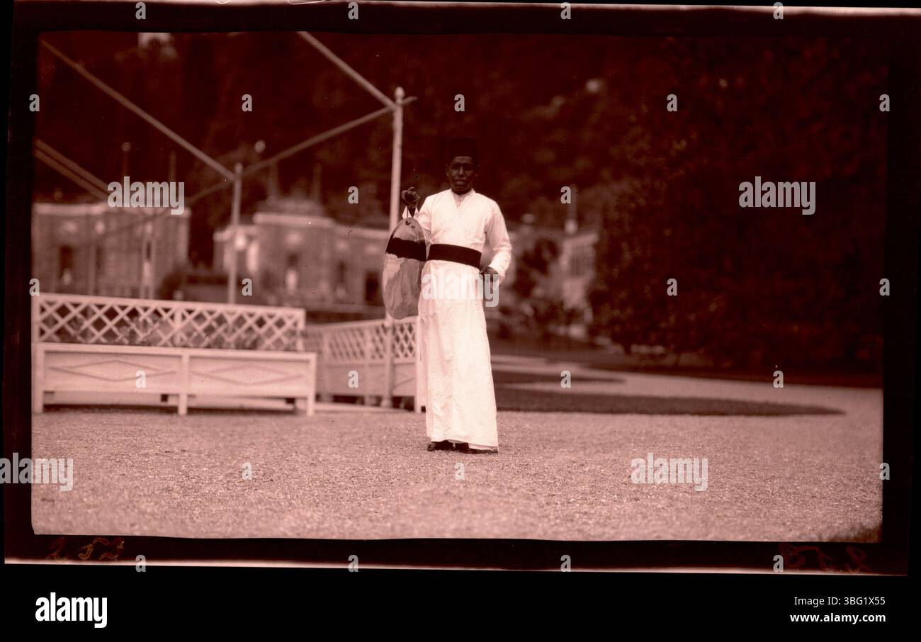 In 1913, a man in a white robe and fez is seen holding a dinner gong ...