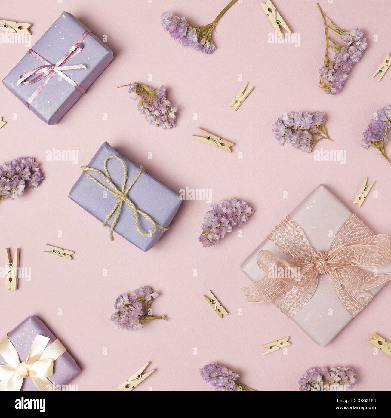 Pastel pink and purple gift boxes with dry flowers and wooden clips on ...