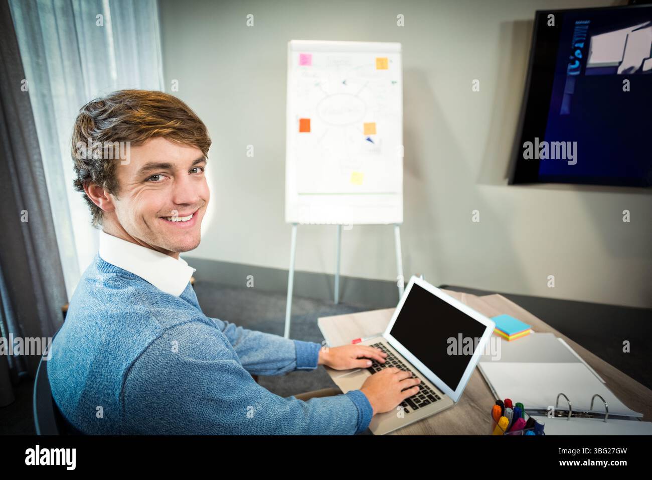 Laptop sitting on desk in meeting room, with binder, colorful markers ...