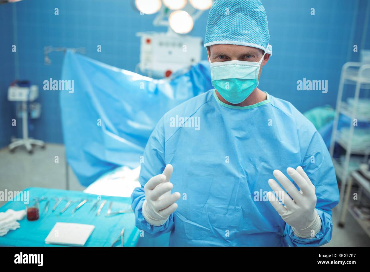 Surgeon standing in operating room adjusting gloves near instrument ...