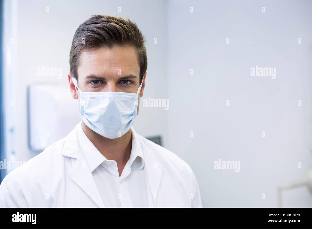 White male healthcare worker standing in clinic wearing lab coat and ...