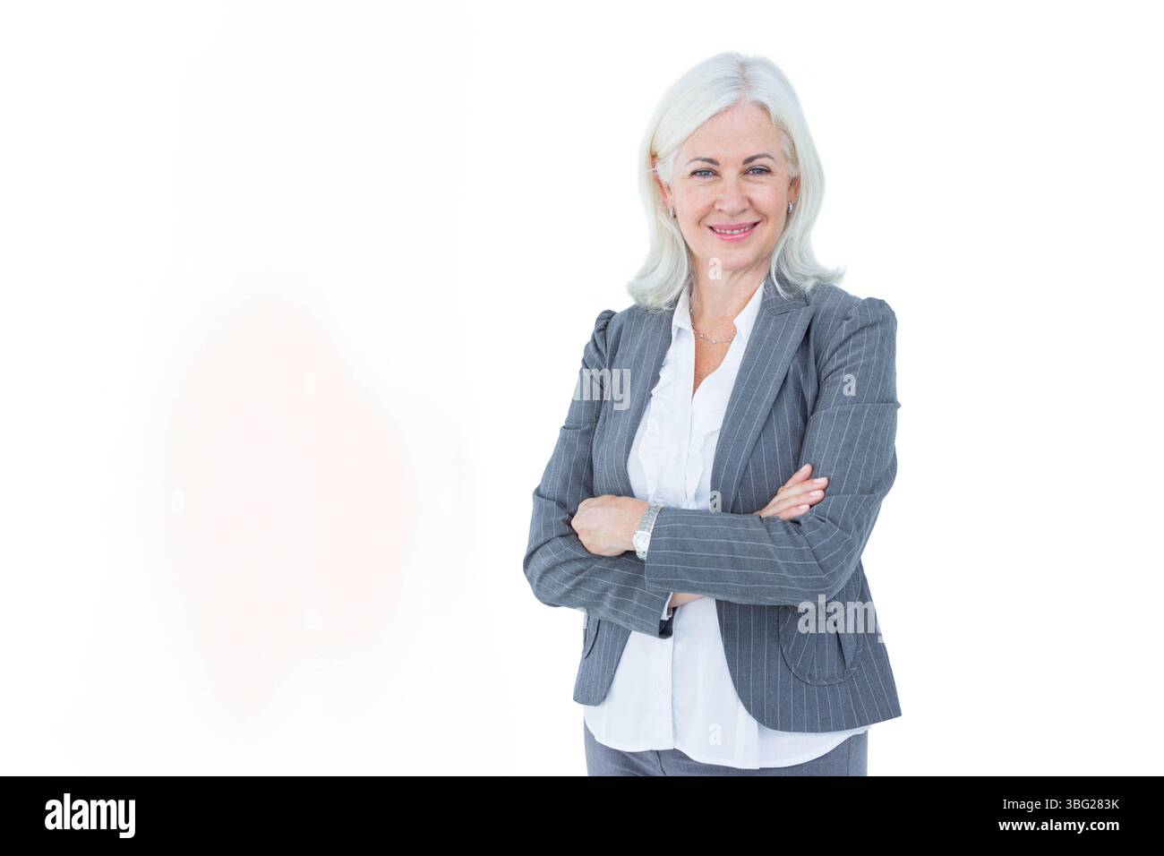 Senior female professional standing with crossed arms in studio wearing ...