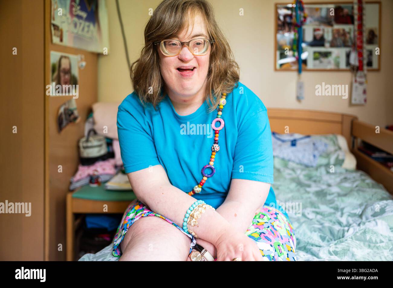Portrait of a 42 yo happy woman with Down Syndrome in her sleeping room ...
