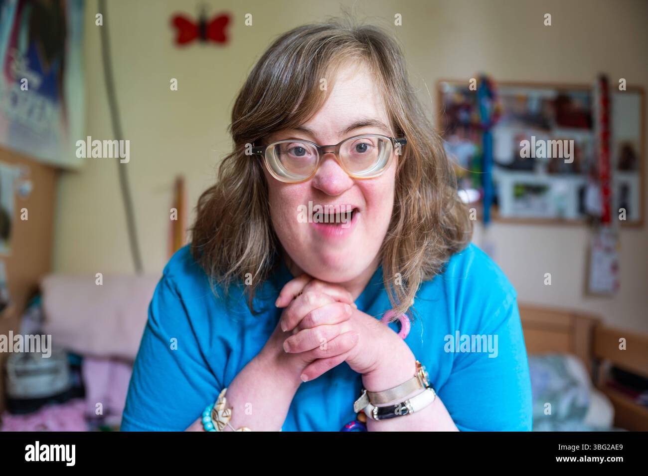 Portrait of a 42 yo happy woman with Down Syndrome in her sleeping room ...