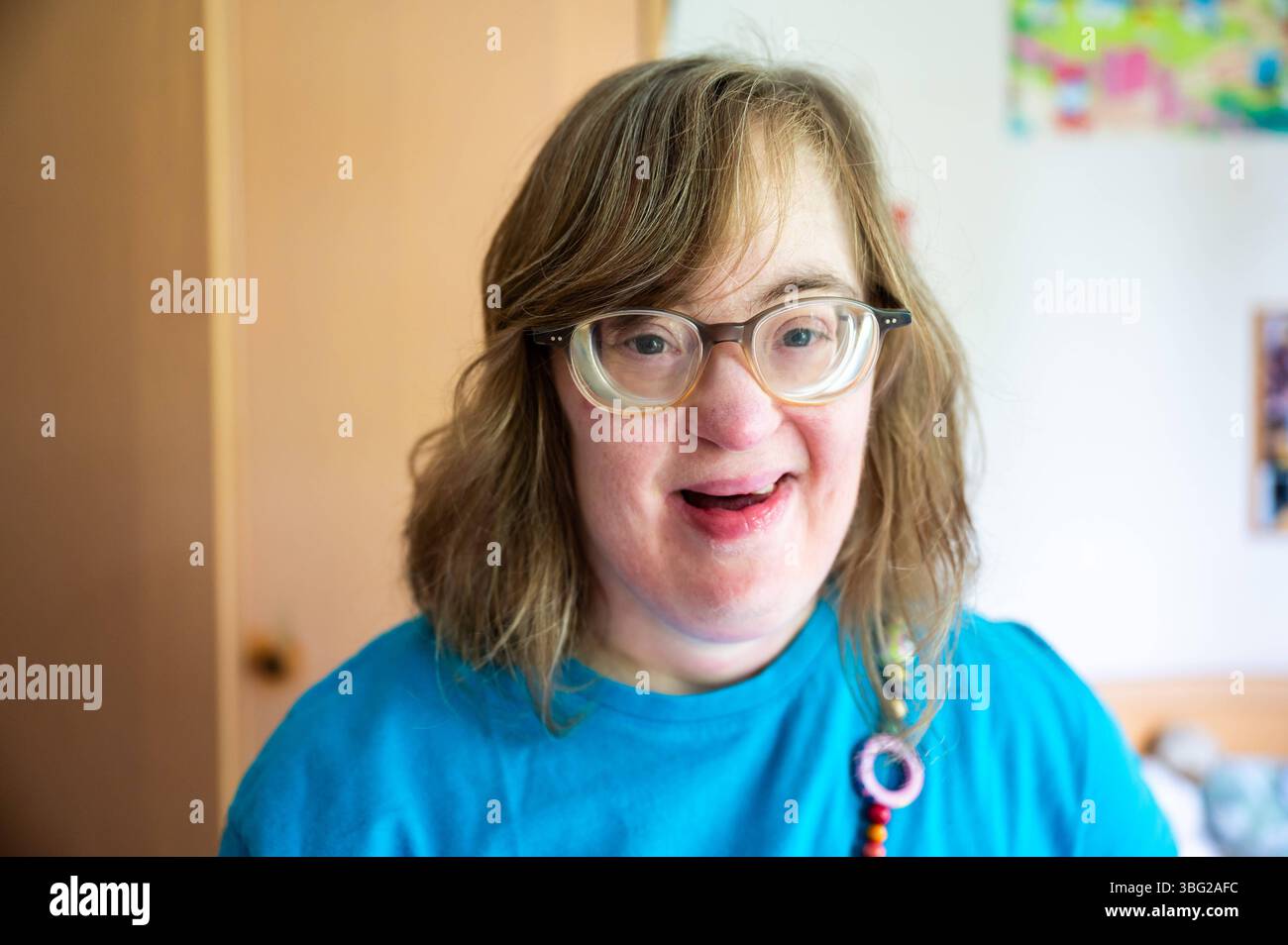 Portrait of a 42 yo happy woman with Down Syndrome in her sleeping room ...